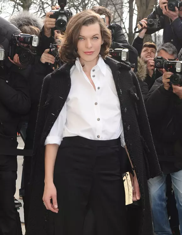 Milla Jovovich carregando uma bolsa Chanel em ouro no desfile de outono 2013 da Chanel