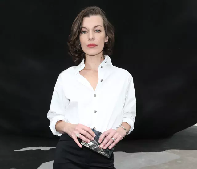 Milla Jovovich carregando uma clutch dourada da Chanel no desfile da Chanel Fall 2013